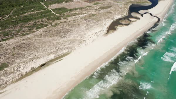 A wide shot of the beach with waves hitting the shore and a view of the ...