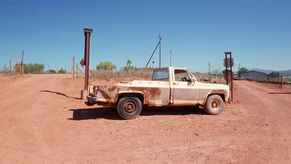 Pan shot of an old white rusty truck parked beside an old rusty pole in ...