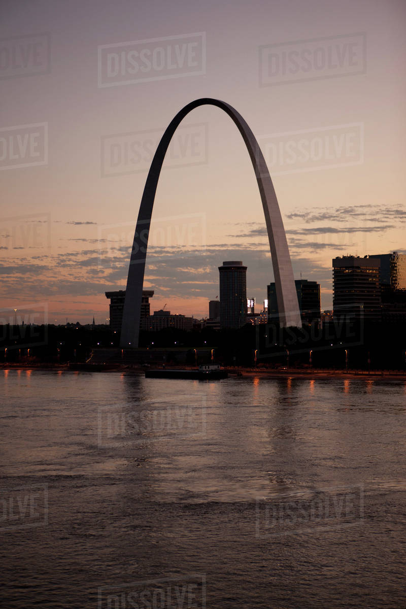Arch landmark next to urban river at sunset - Stock Photo - Dissolve