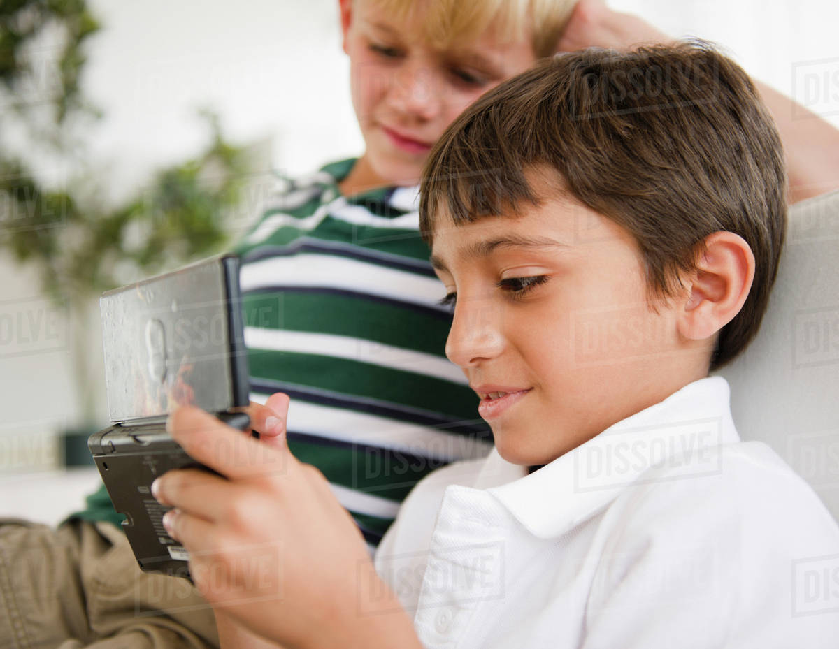 Boy watching friend playing hand-held video game - Royalty-free Stock ...