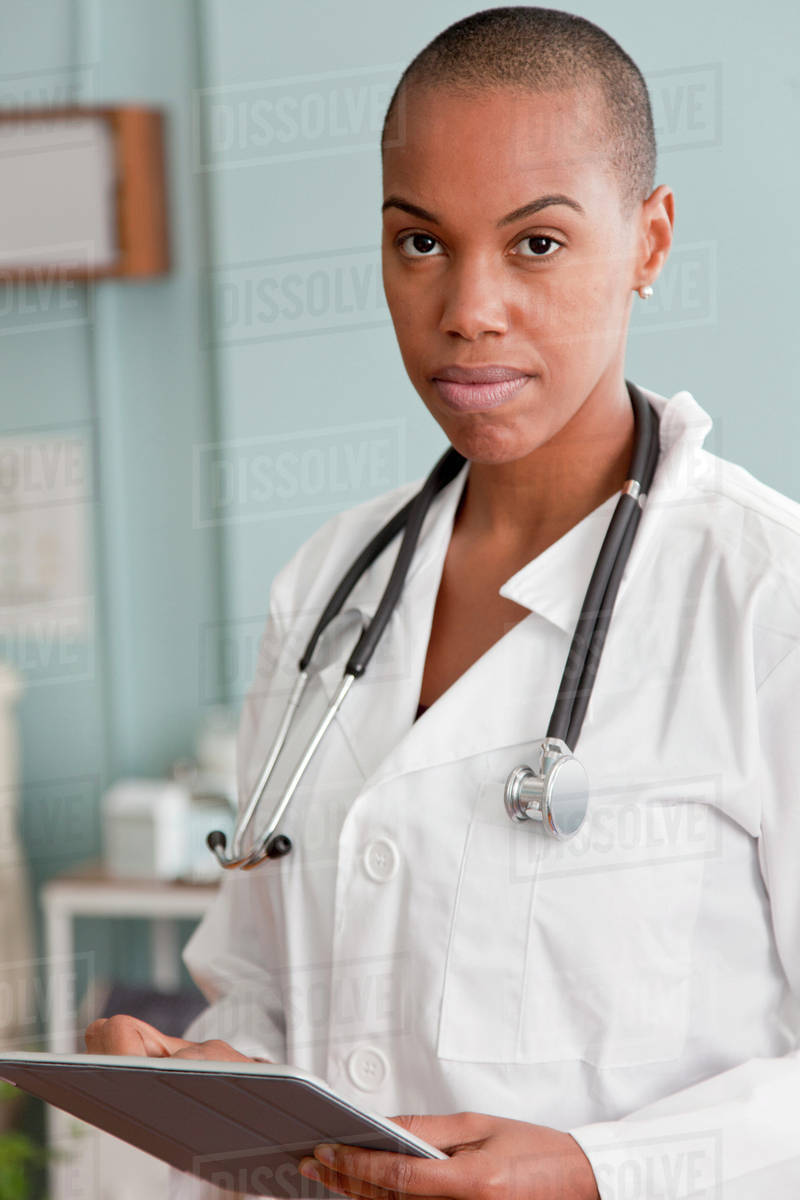 Serious Black doctor using digital tablet - Stock Photo - Dissolve