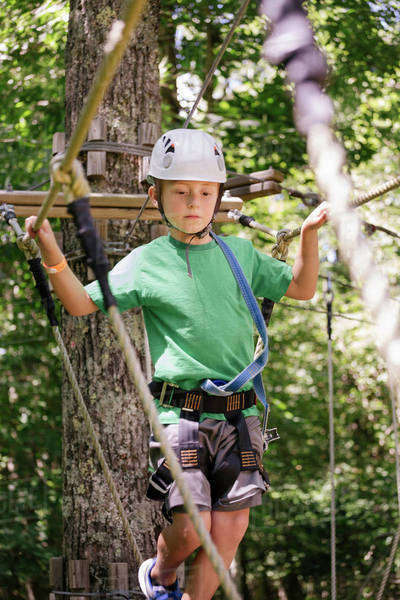 Caucasian boy balancing on rope bridge - Stock Photo - Dissolve