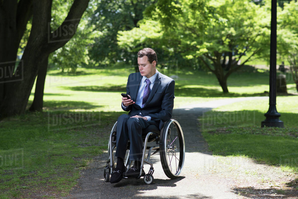 Paraplegic businessman in wheelchair in park - Stock Photo - Dissolve