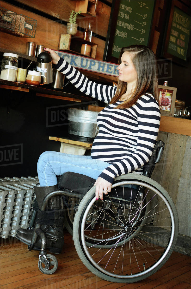 Paraplegic woman in wheelchair pouring coffee in cafe - Royalty-free ...