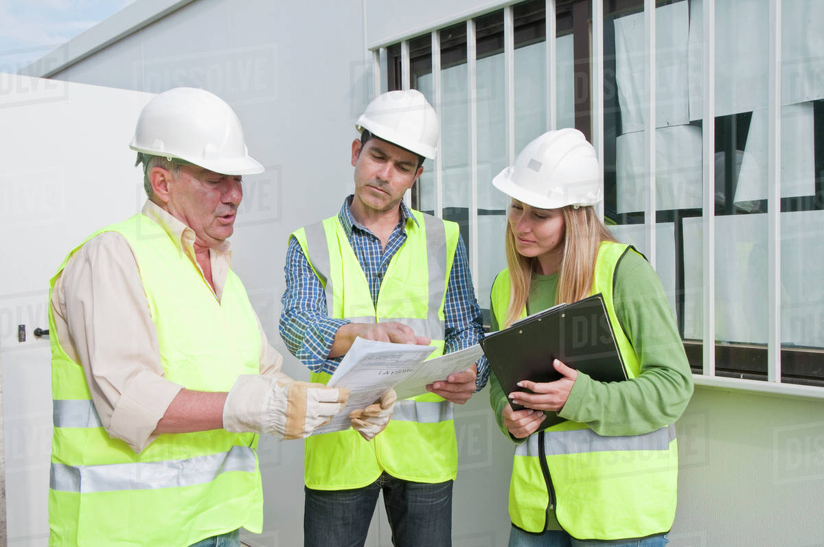Hispanic construction workers reviewing paperwork - Stock Photo - Dissolve