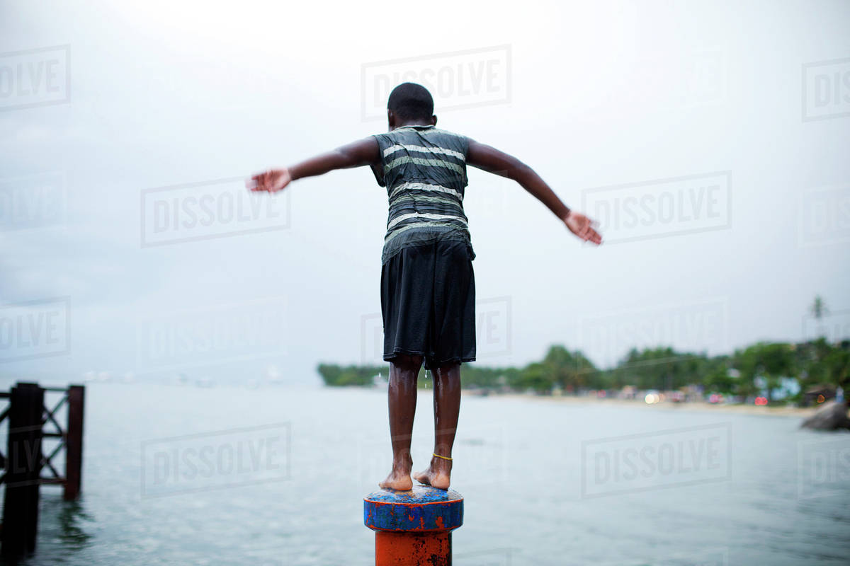 Boy on pipe about to jump in the water - Stock Photo - Dissolve