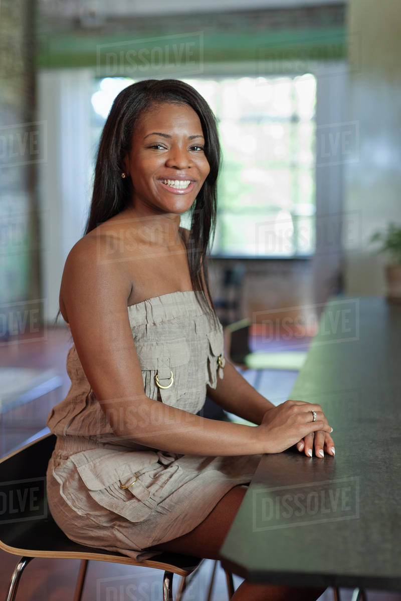 Smiling Black woman sitting at counter - Royalty-free Stock Photo ...