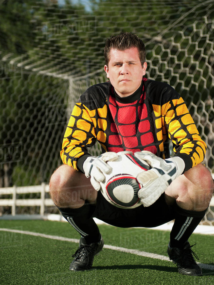 Mixed race goalkeeper crouching with soccer ball - Royalty-free Stock ...
