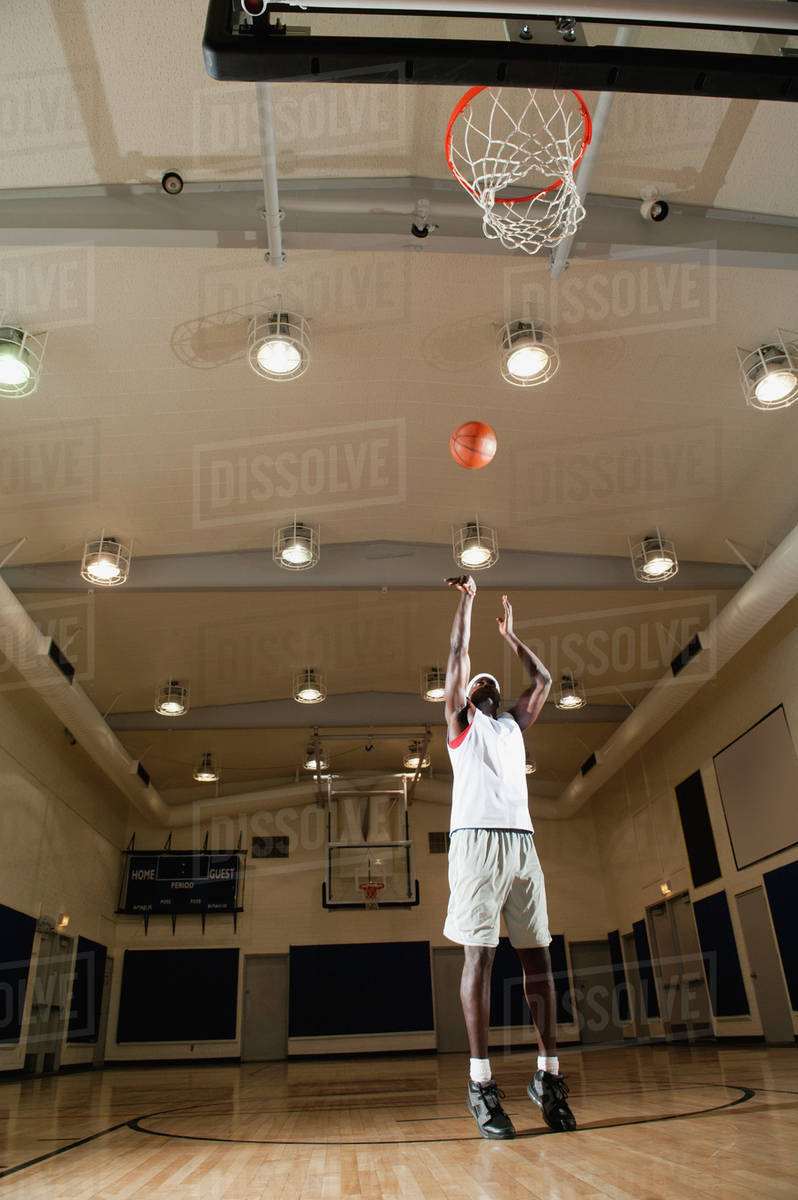 Black man shooting basketball on basketball court - Stock Photo - Dissolve