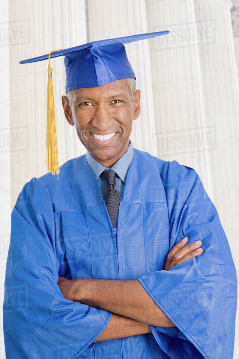 Mixed race man in graduation cap and gown - Stock Photo - Dissolve