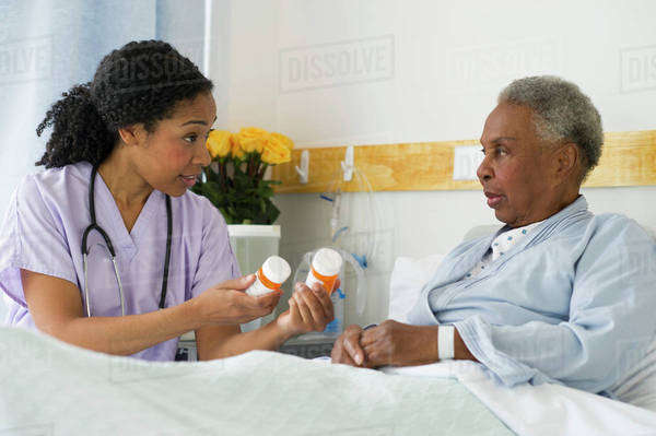 Nurse explaining medication to patient in hospital bed - Royalty-free ...
