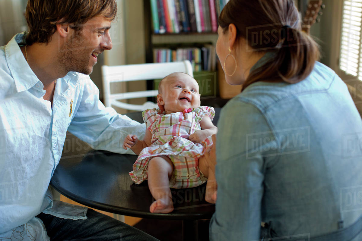 Happy Caucasian parents admiring baby daughter - Stock Photo - Dissolve