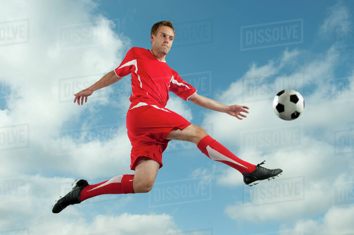 Soccer player jumping in mid-air kicking ball - Royalty-free Stock ...