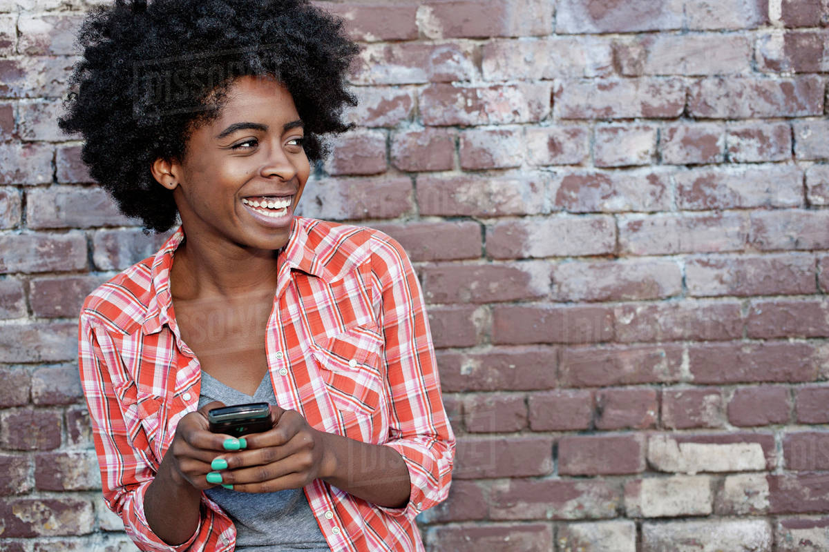 Black woman text messaging on cell phone - Stock Photo - Dissolve