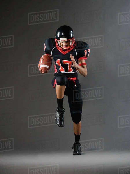 Mixed race football player running with football - Royalty-free Stock ...