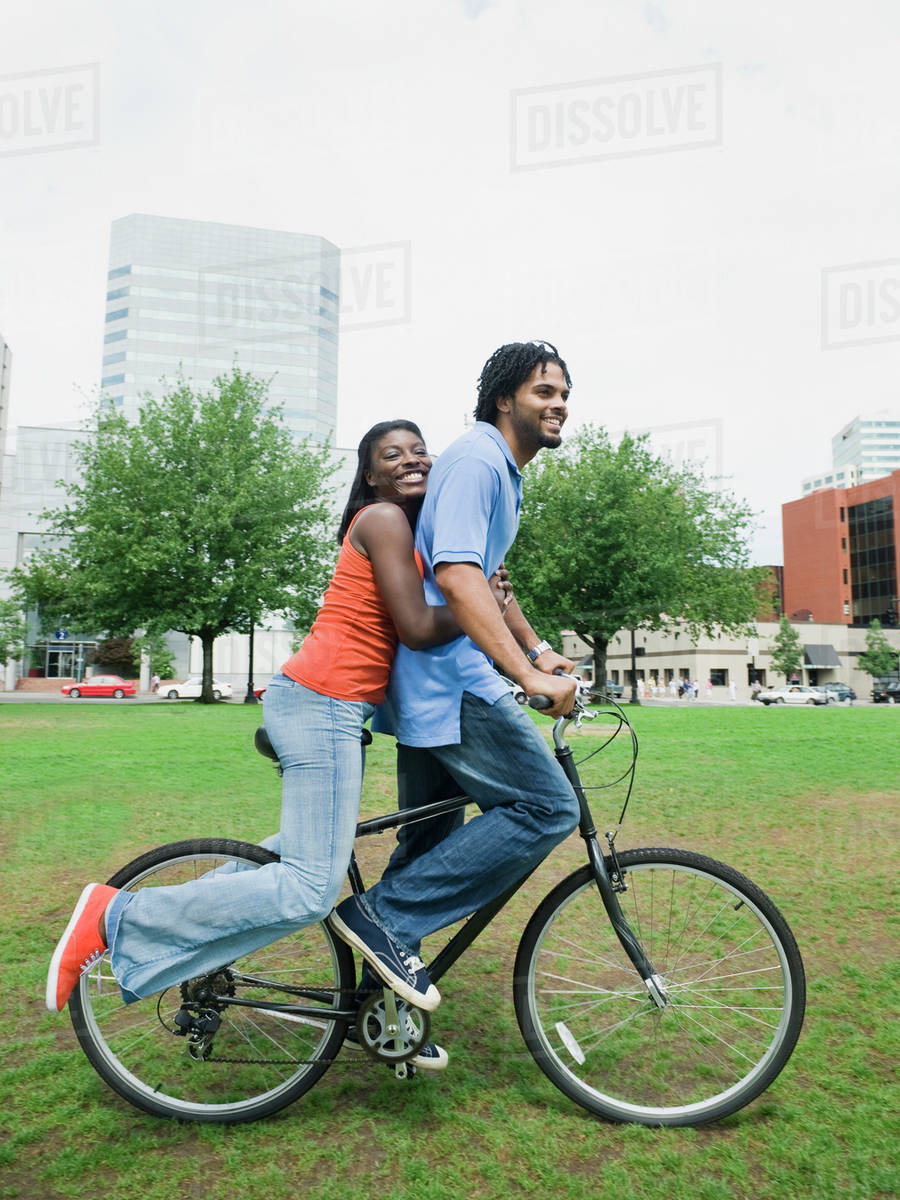 Couple riding bicycle in urban park - Royalty-free Stock Photo | Dissolve