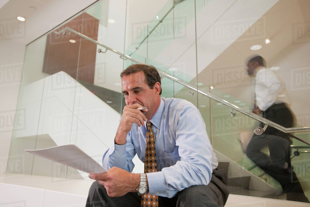 Businessman reviewing paperwork in office lobby - Royalty-free Stock ...