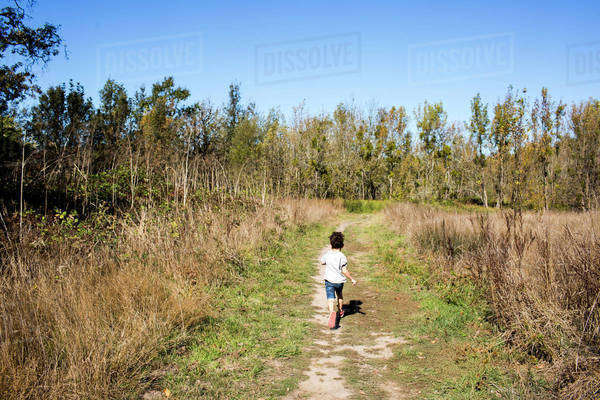 Mixed race boy walking on dirt path - Royalty-free Stock Photo | Dissolve
