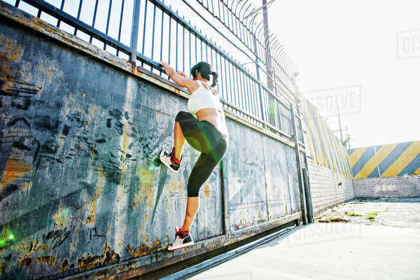 Mixed race woman climbing gate - Royalty-free Stock Photo | Dissolve