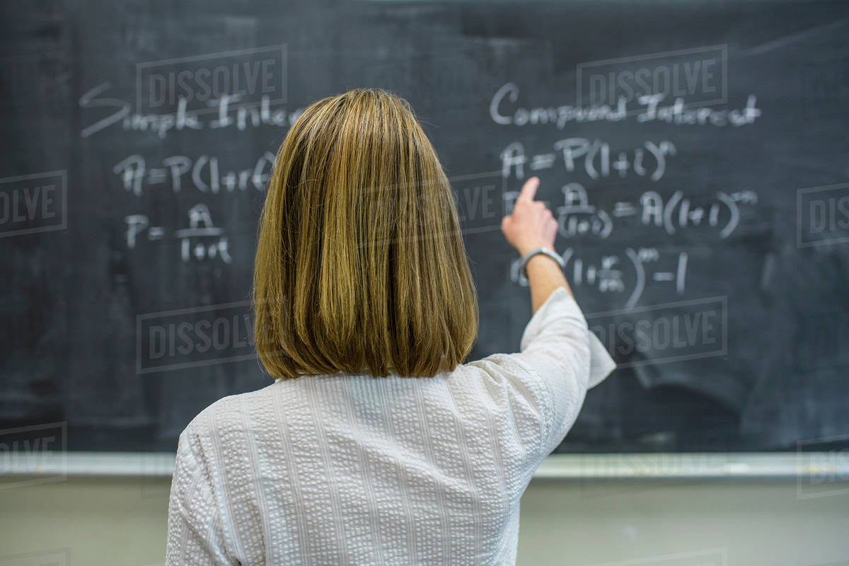 Caucasian teacher pointing to chalkboard - Royalty-free Stock Photo ...