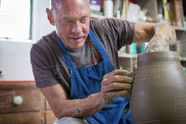 Older Caucasian man forming pottery on wheel in ceramics studio ...