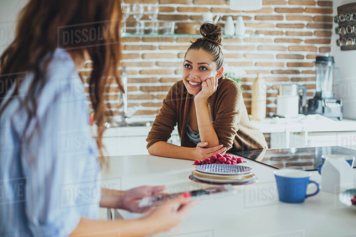 Caucasian women talking in kitchen - Royalty-free Stock Photo | Dissolve