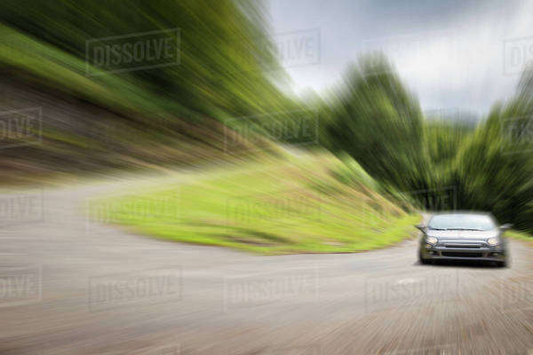 Blurred view of car driving on curved road - Stock Photo - Dissolve