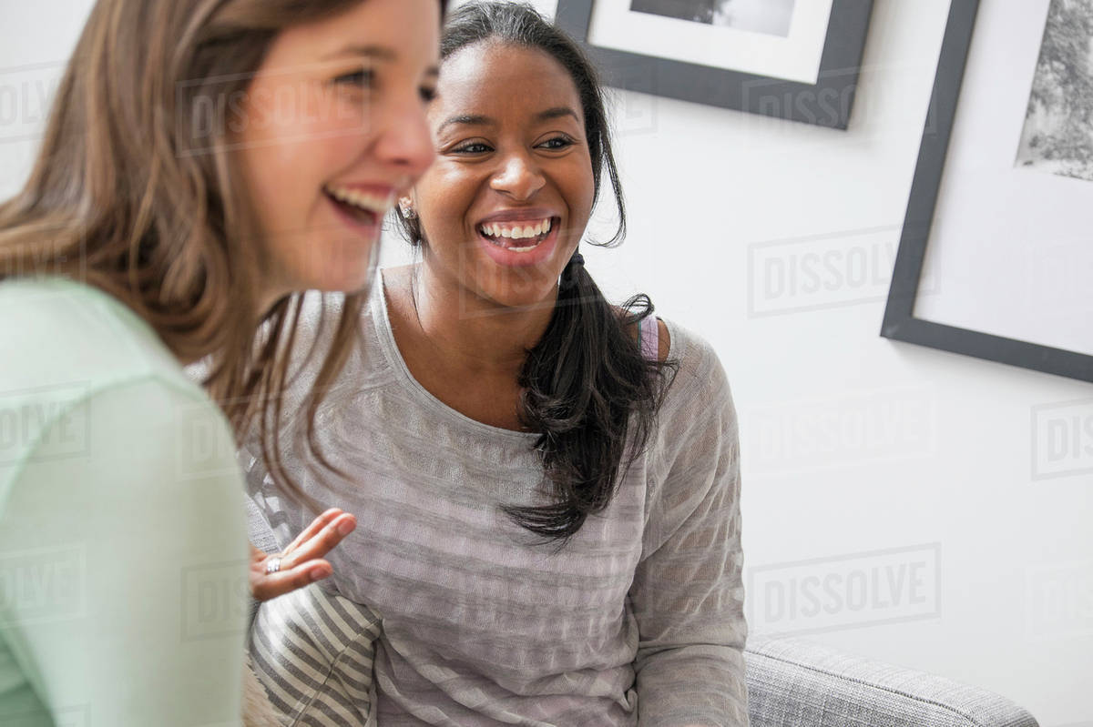 Smiling women talking on sofa - Royalty-free Stock Photo | Dissolve