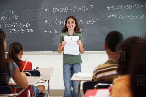 Girl holding up paper in front of class - Stock Photo - Dissolve