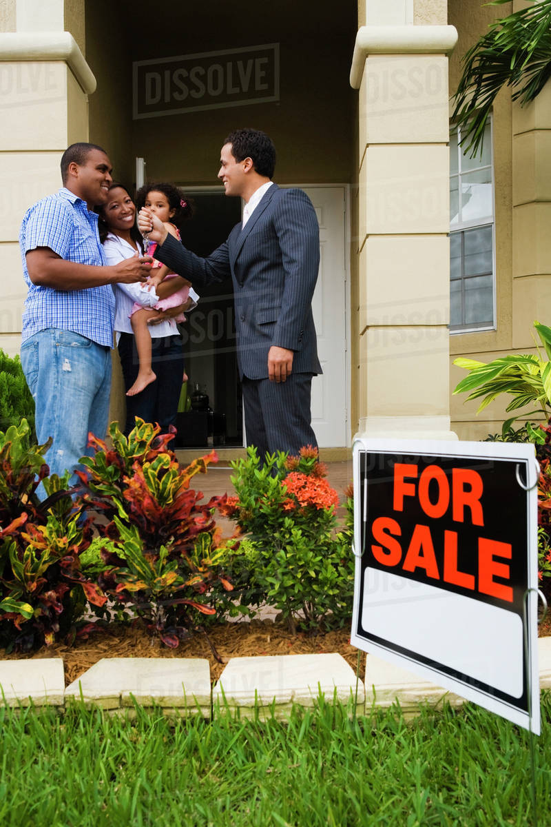 Hispanic real estate agent giving house keys to African family - Stock ...