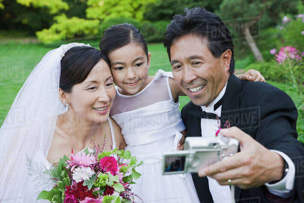 Asian newlyweds and daughter taking own photograph - Royalty-free Stock ...