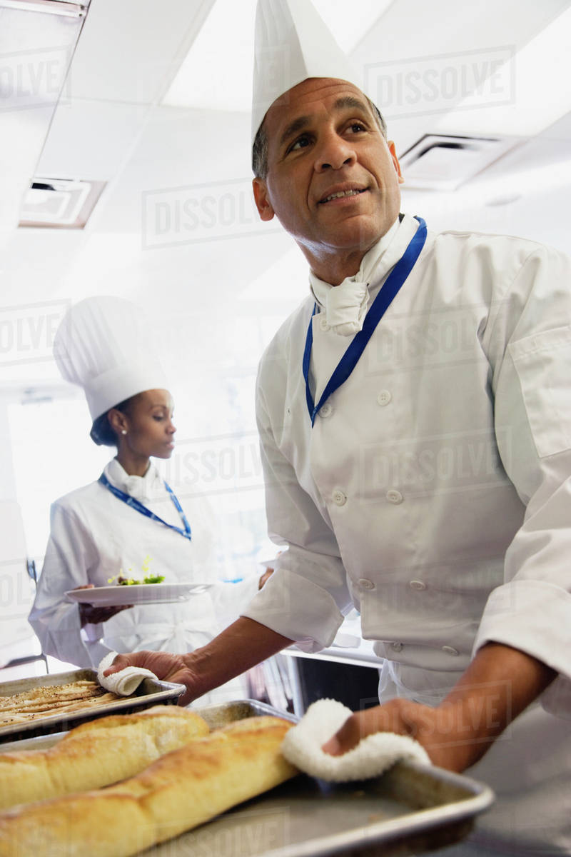 Multi-ethnic chefs carrying food in kitchen - Royalty-free Stock Photo ...
