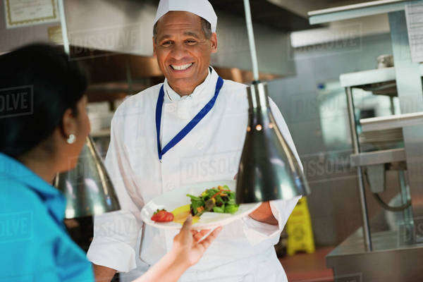 African male chef handing out plate of food - Royalty-free Stock Photo ...