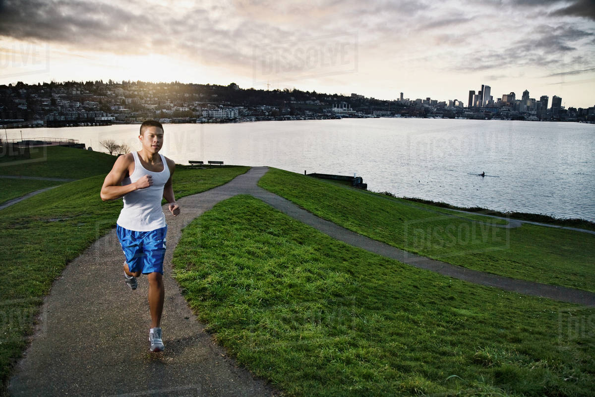 Asian man jogging along urban waterfront - Royalty-free Stock Photo ...