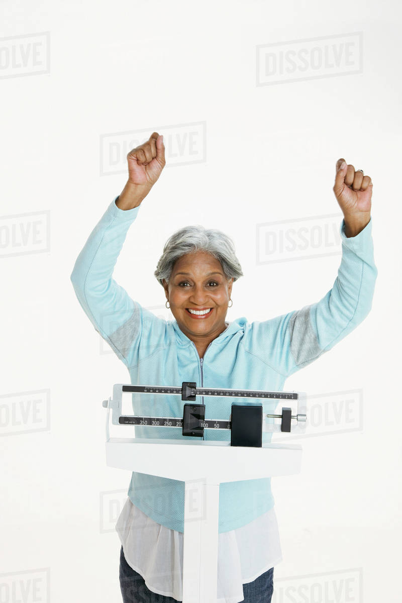 African woman weighing herself on scale - Royalty-free Stock Photo ...