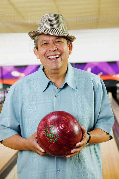 Hispanic man holding bowling ball - Stock Photo - Dissolve