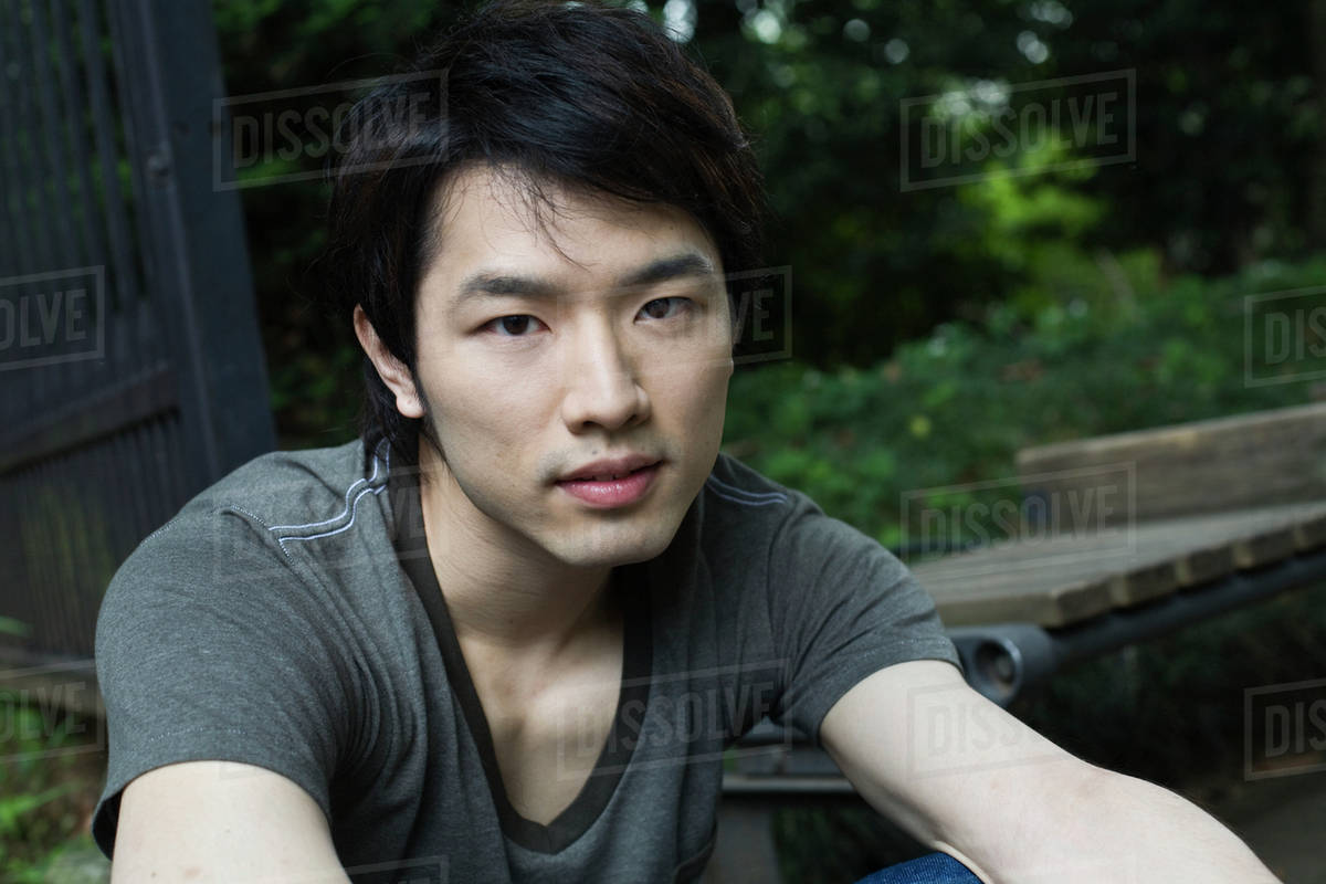 Serious Japanese man sitting outdoors - Royalty-free Stock Photo | Dissolve