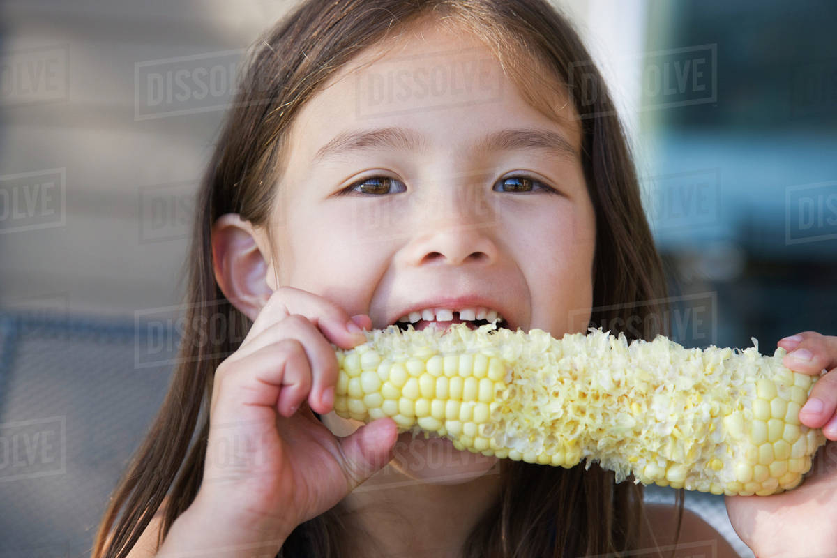 Asian girl eating corn on the cob - Royalty-free Stock Photo | Dissolve