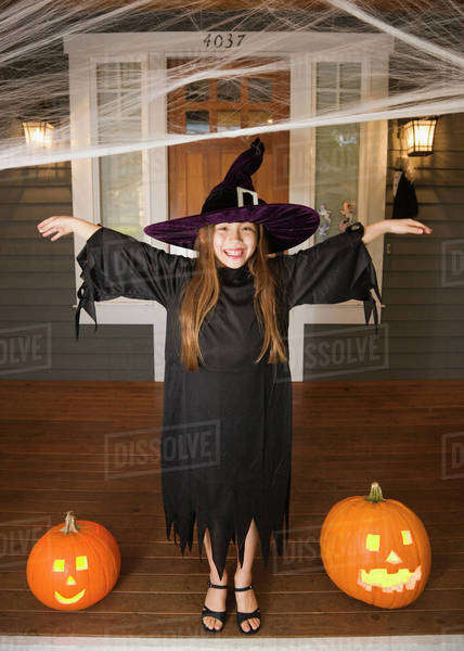 Mixed race young girl in witch costume with Halloween pumpkins ...