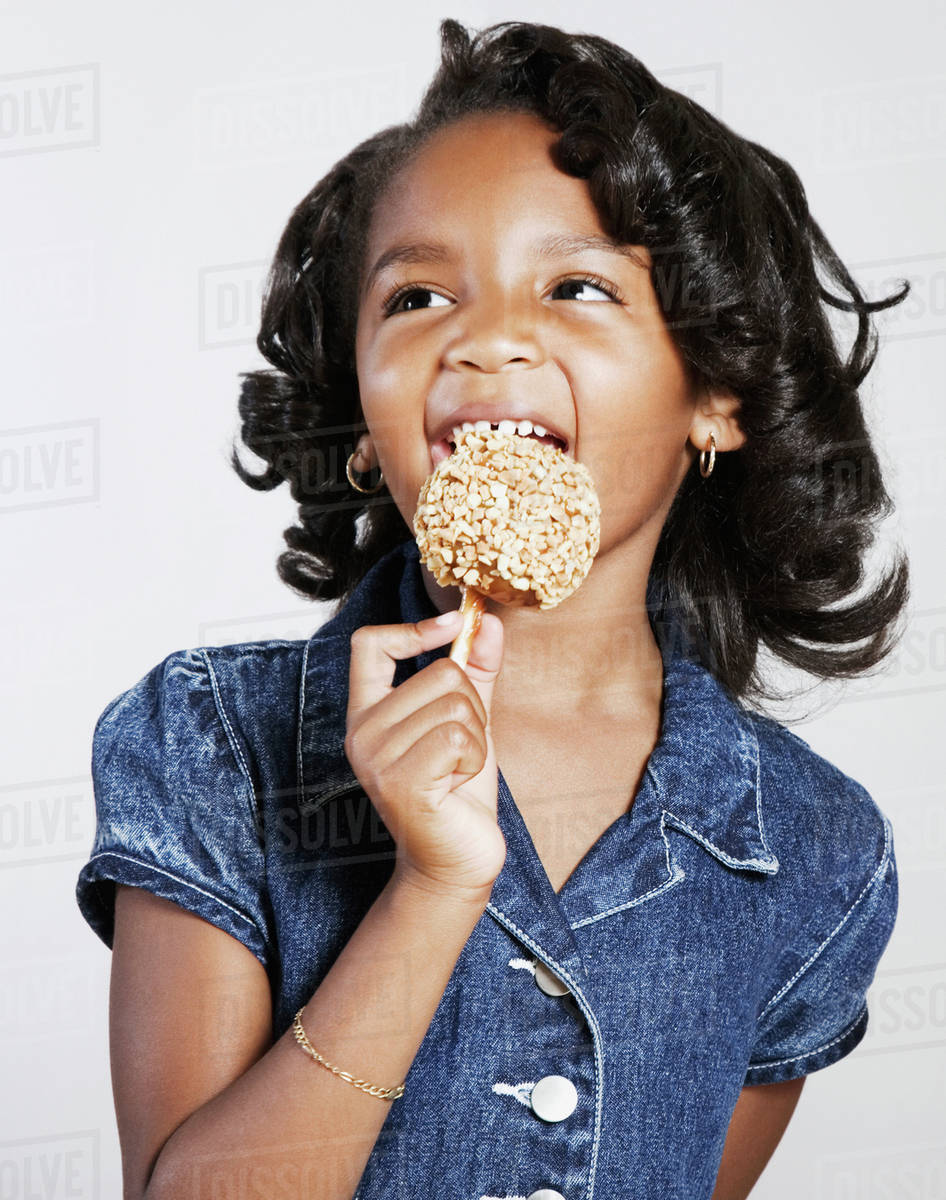 African girl eating candy apple - Royalty-free Stock Photo | Dissolve