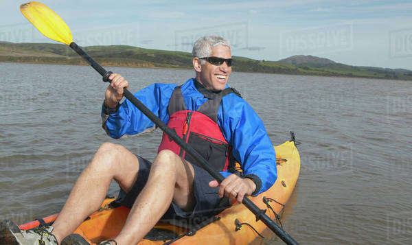 Middle-aged man rowing a kayak in still water - Stock Photo - Dissolve