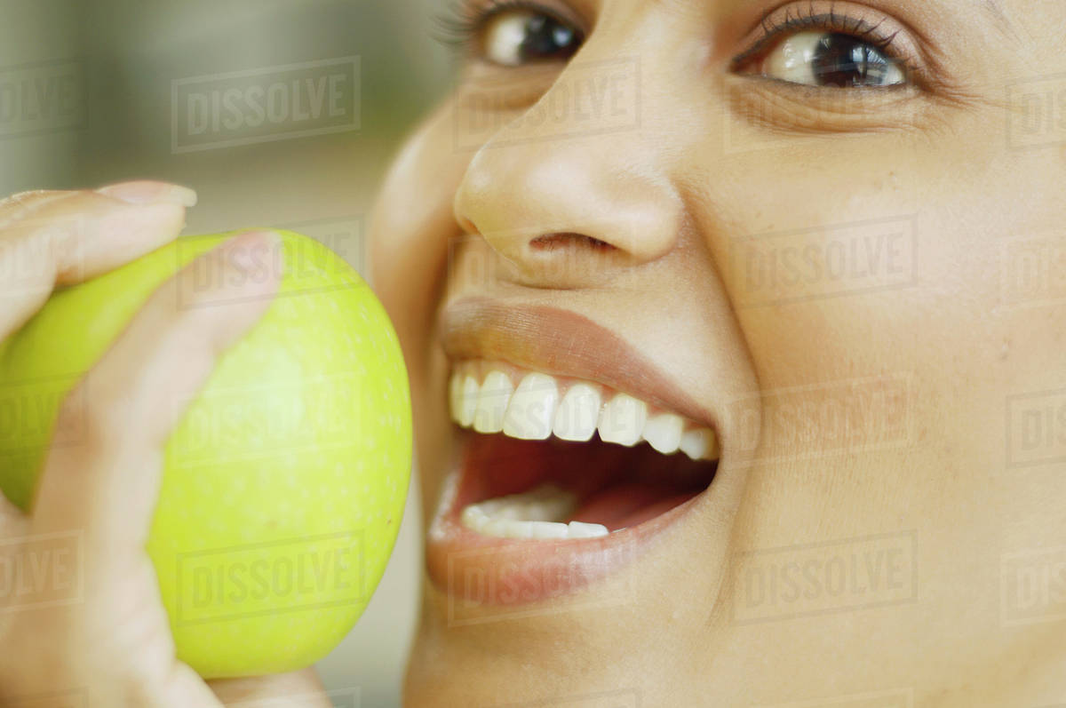 Close up of woman about to bite into an apple - Stock Photo - Dissolve