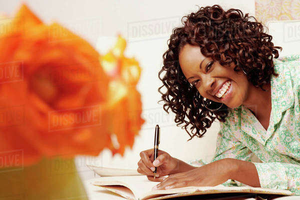 African woman writing in book - Royalty-free Stock Photo | Dissolve