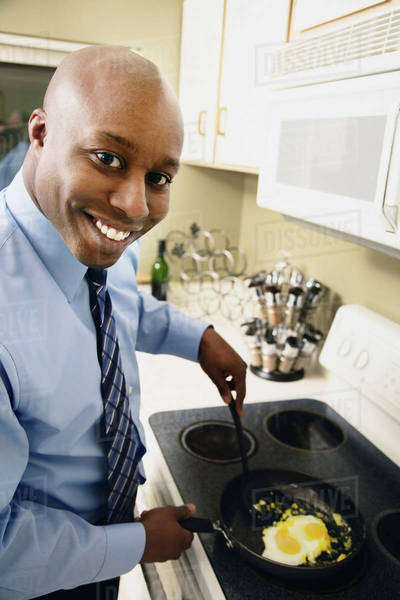African man cooking eggs in kitchen - Stock Photo - Dissolve