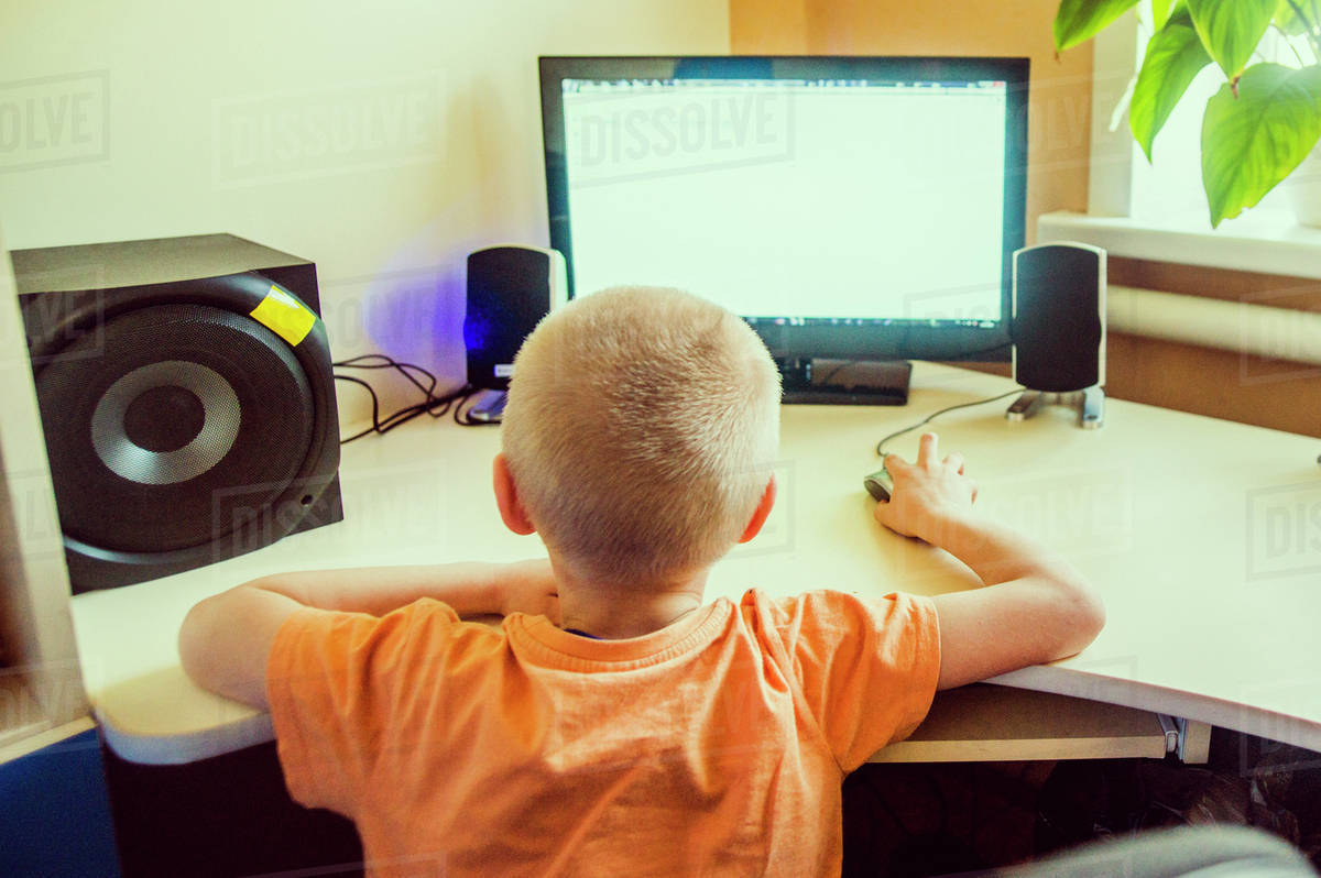 Caucasian boy using computer at desk - Royalty-free Stock Photo | Dissolve