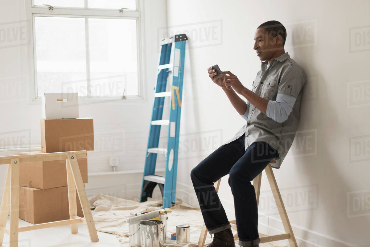 Black man sitting in room under renovation - Stock Photo - Dissolve