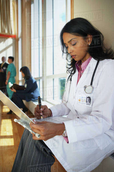 Female Indian doctor marking on a chart - Royalty-free Stock Photo ...