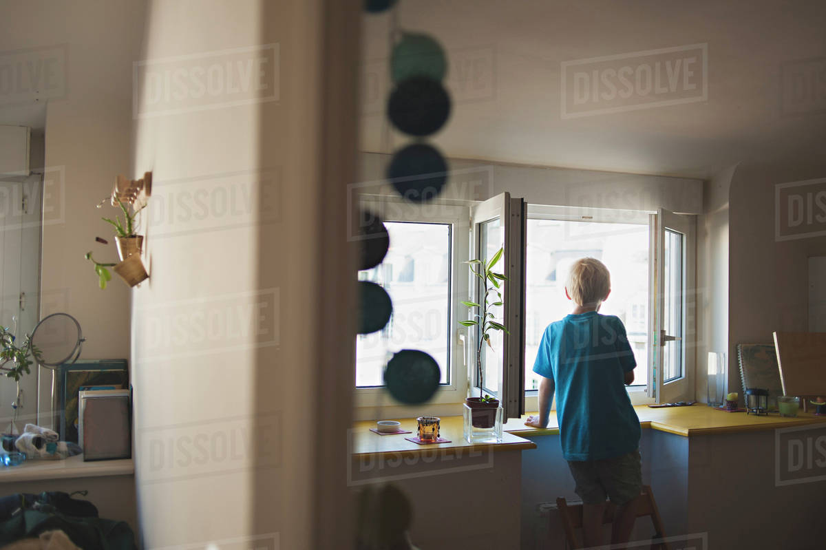 Caucasian boy looking out kitchen window - Royalty-free Stock Photo ...