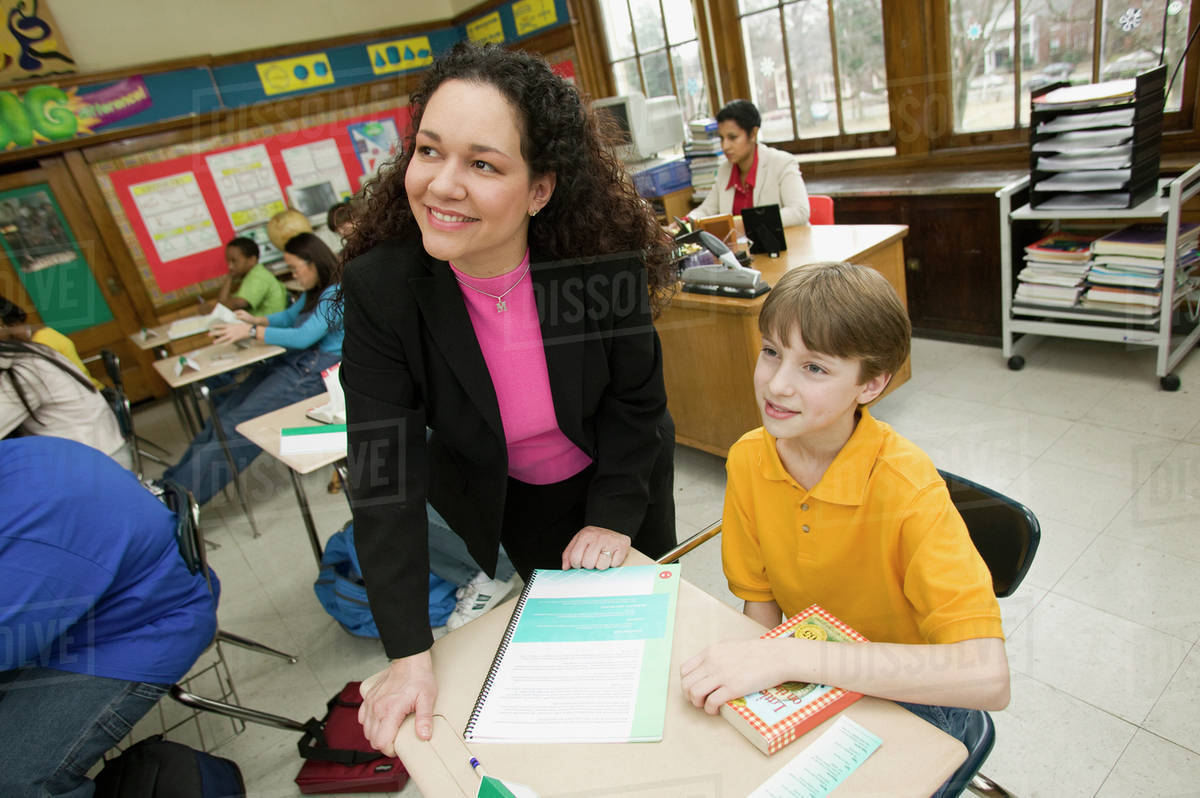 Hispanic school teacher helping student - Stock Photo - Dissolve