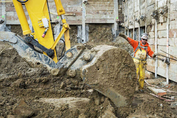 Caucasian worker directing digger at construction site - Stock Photo ...